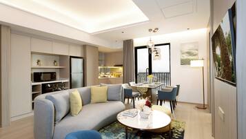 Uma sala de estar moderna com um sofá cinza, poltronas azuis, uma mesa de centro redonda e um espaço de jantar com mesa e cadeiras.
