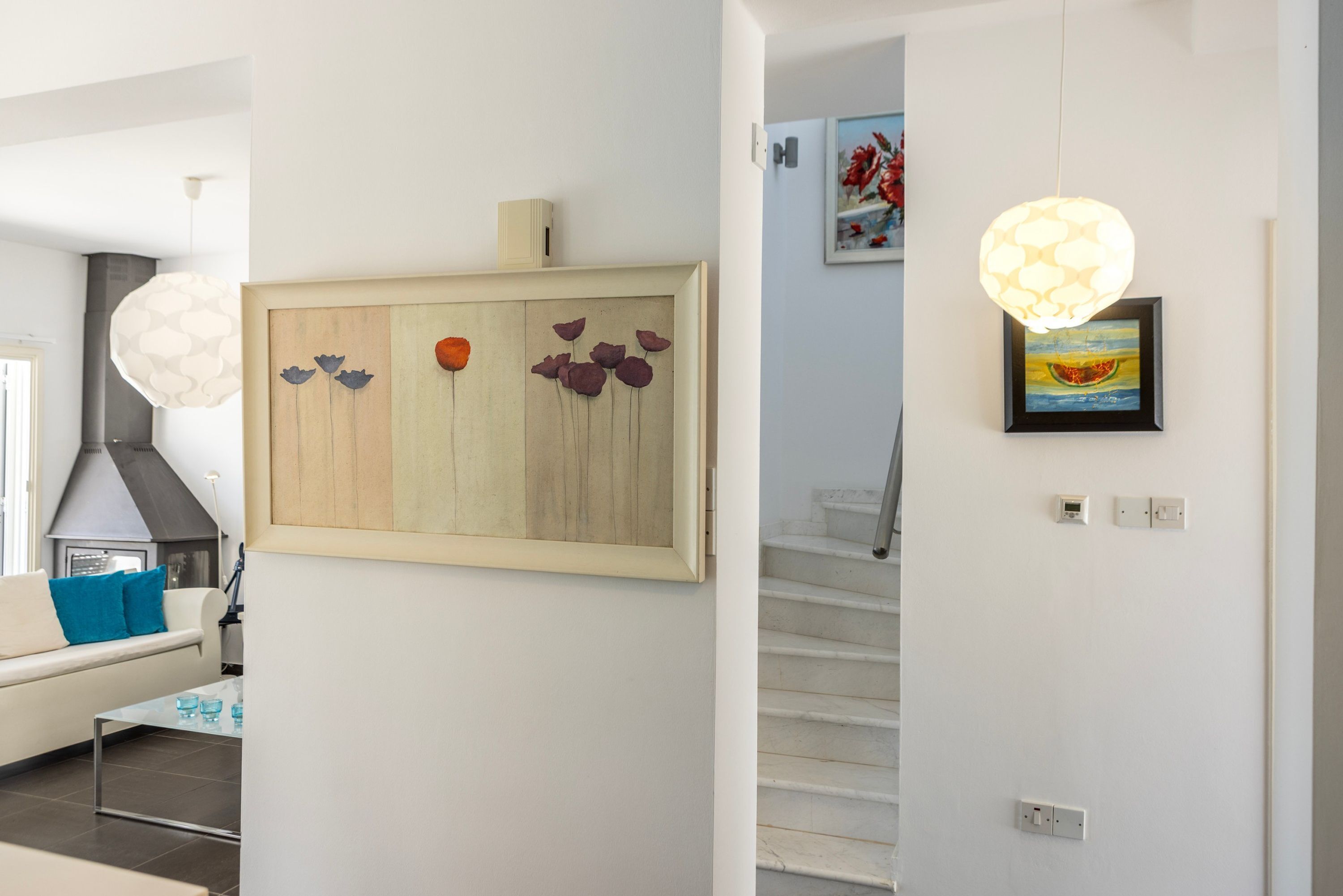 Um interior moderno com uma escada, uma obra de arte emoldurada e uma luminária única.