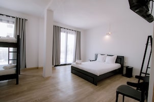 Quarto de hotel moderno com cama de solteiro, uma cama grande, uma escrivaninha e uma cadeira.