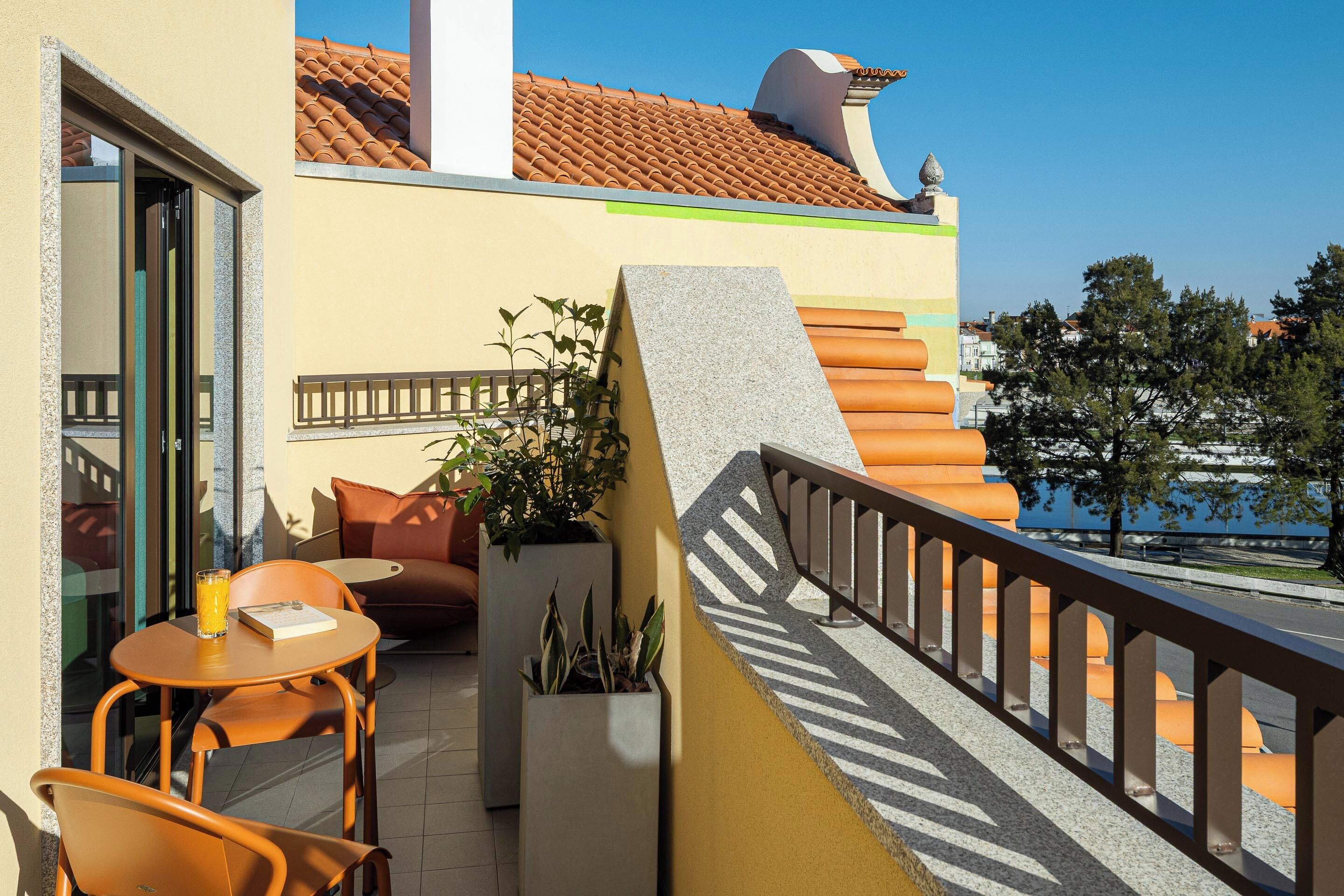 Uma varanda com mesa e cadeiras, uma escadaria e vista para o mar.