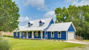 Uma casa de dois andares com fachada azul, varanda coberta e garagem.