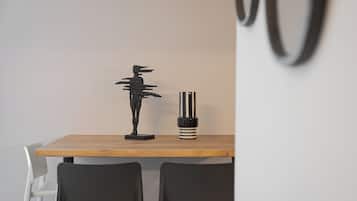 Uma mesa de madeira com uma escultura preta e um vaso listrado.
