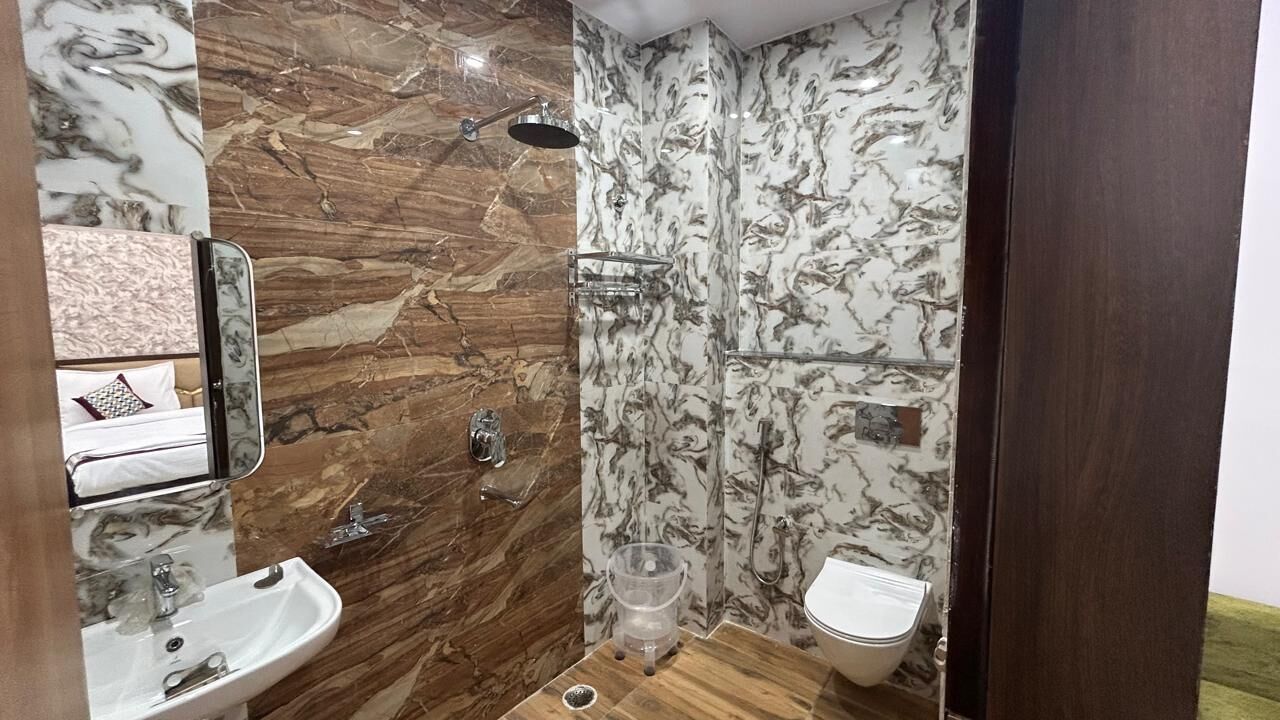 Casa de banho com chuveiro de mármore, lavatório e sanita.