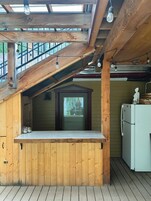 Uma cabana de madeira com cozinha, uma pequena mesa de jantar e escada que leva a um andar superior.