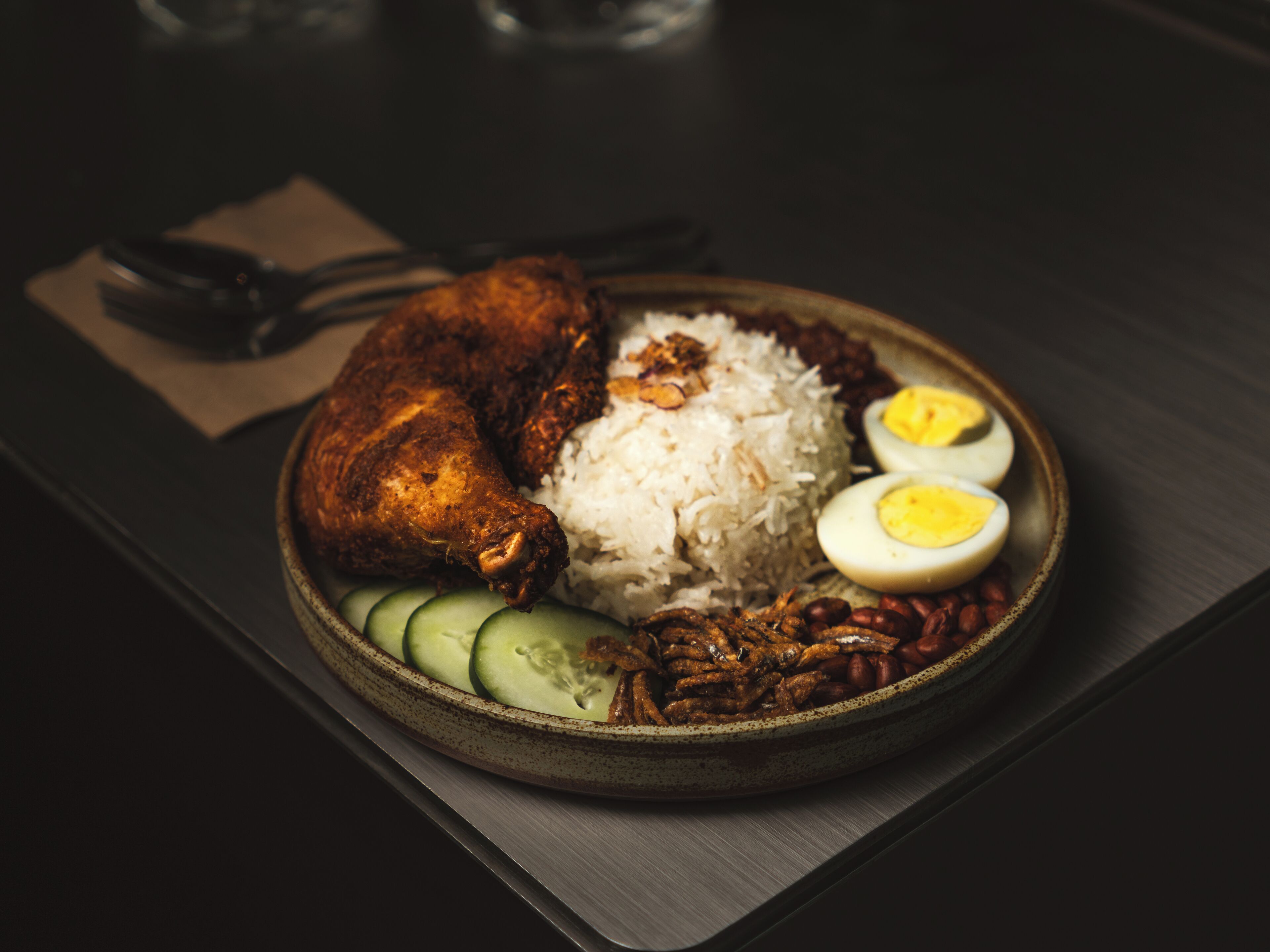 Prato com arroz, ovo cozido, fatias de pepino e amendoins.