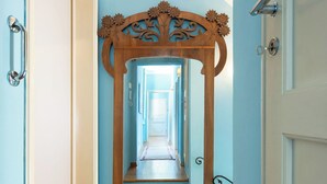 Um corredor com escada de madeira que leva a uma porta com arco decorativo.