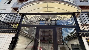 Um edifício alto com uma entrada imponente, destacando-se por um toldo e o nome 'Edificio Isabela'.