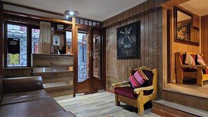 Um quarto acolhedor com piso de madeira, um banco de madeira, uma cadeira estofada e uma escada que leva a outro andar.