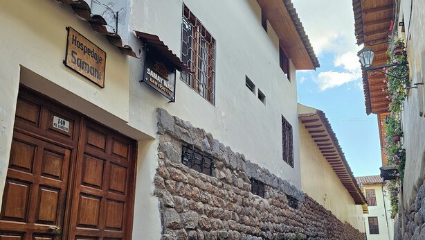 Um edifício tradicional com parede de pedra, porta de madeira e placa indicando um albergue.