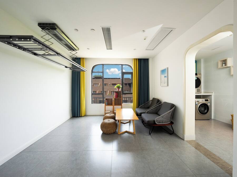 Uma sala de estar moderna com um sofá, uma mesa e uma máquina de lavar ao fundo.