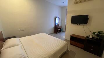 Quarto de hotel com uma cama, televisão na parede, escrivaninha com cadeira e um espelho.
