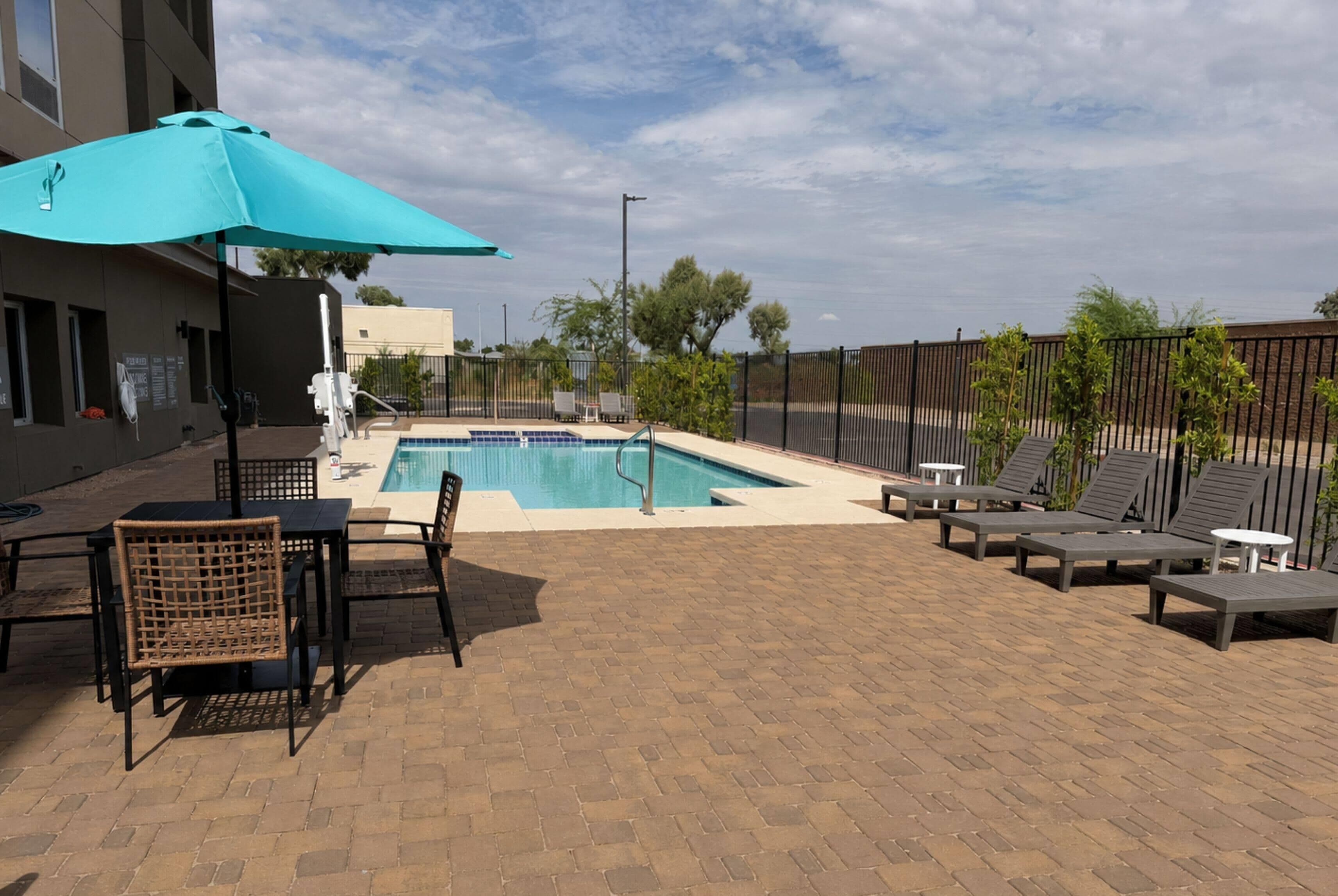 Uma área de piscina com espreguiçadeiras, uma mesa e um espaço de estar coberto.
