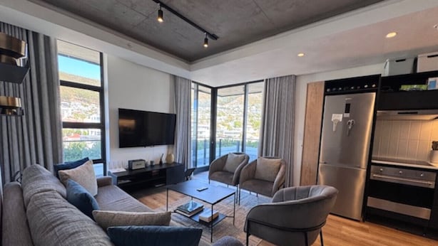 Uma sala de estar moderna com um sofá, poltronas, uma mesa de centro e uma TV de tela plana.