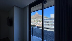 Quarto com uma grande porta de vidro deslizante que dá para uma varanda com vista para uma montanha e edifícios.