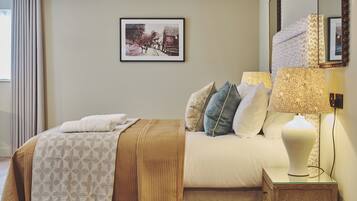 Cama bem arrumada com um edredom estampado, uma luminária de cabeceira e um quadro na parede.