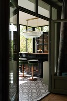 Cozinha moderna com luminária pendente, dois banquetas e piso estampado.