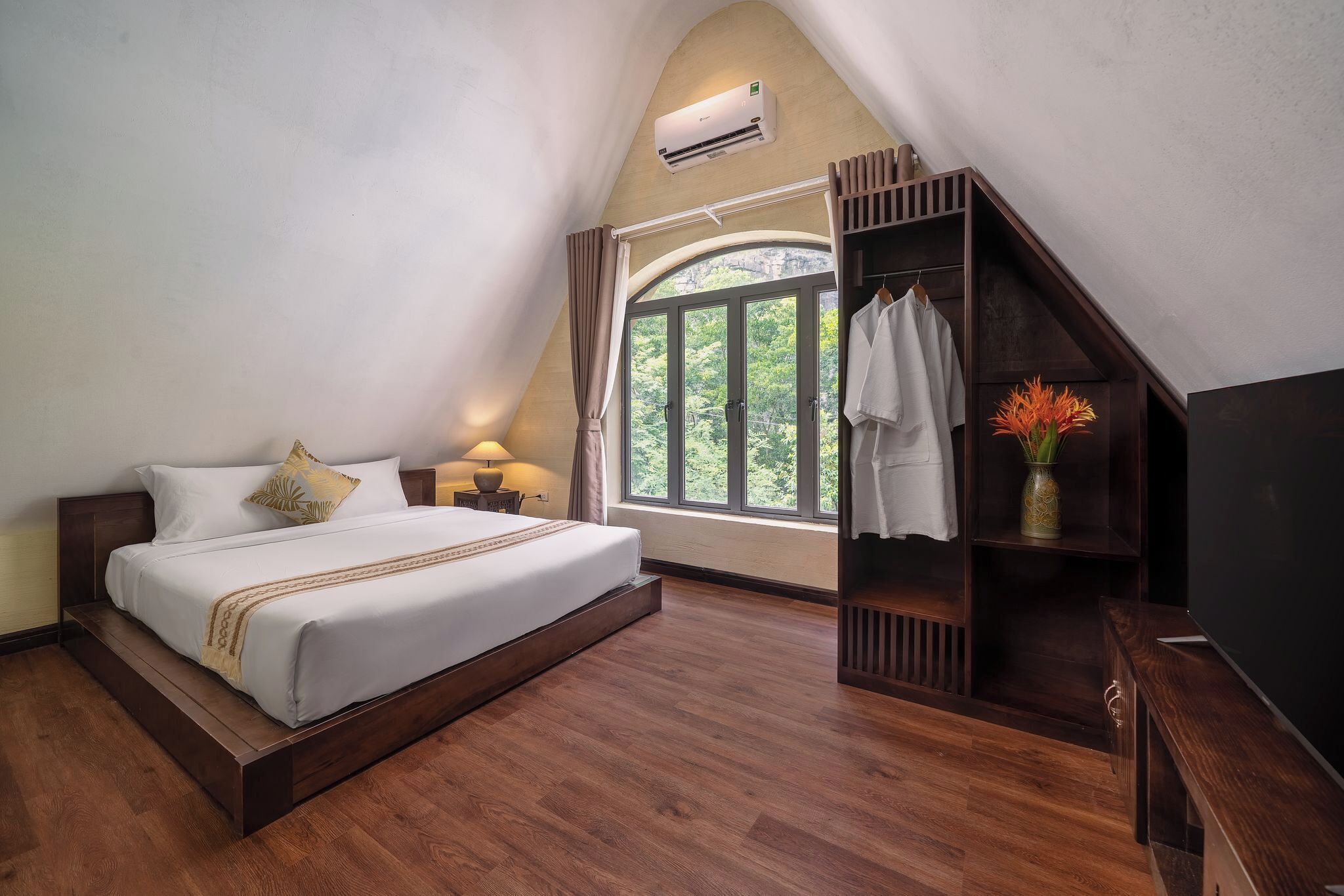 Quarto com cama, guarda-roupa de madeira, janela com cortinas e ar condicionado.