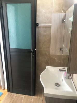 Casa de banho com porta preta, lavatório branco e espelho.