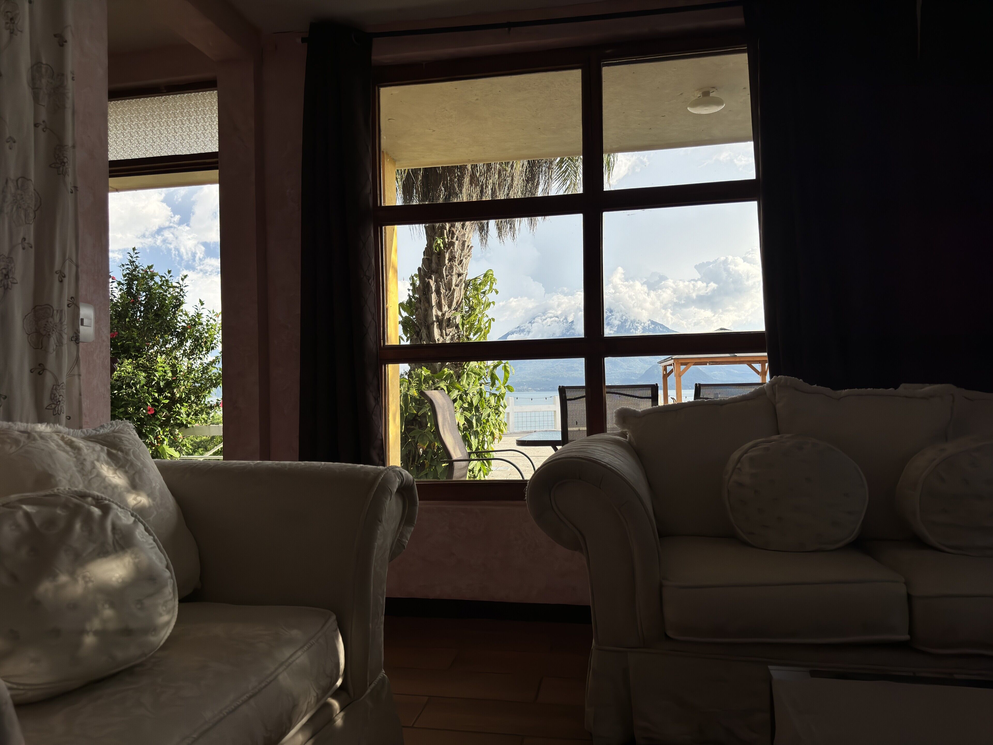 Quarto com dois sofás de frente para uma janela ampla com vista para uma paisagem montanhosa.