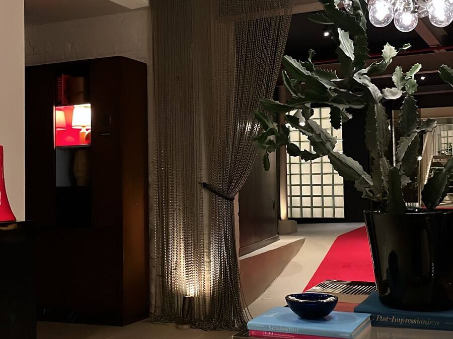 Uma sala de estar moderna com um lustre, um vaso de planta e uma estante de livros.