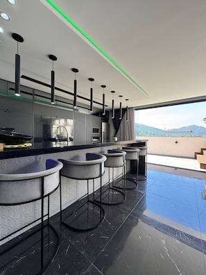 Cozinha moderna com área de bar, banquetas e iluminação pendente.