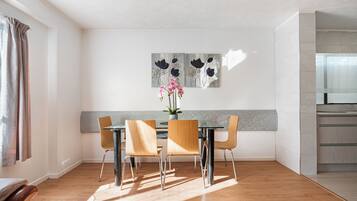 Uma sala de jantar moderna com uma mesa de vidro, cadeiras de madeira e um vaso de flores.