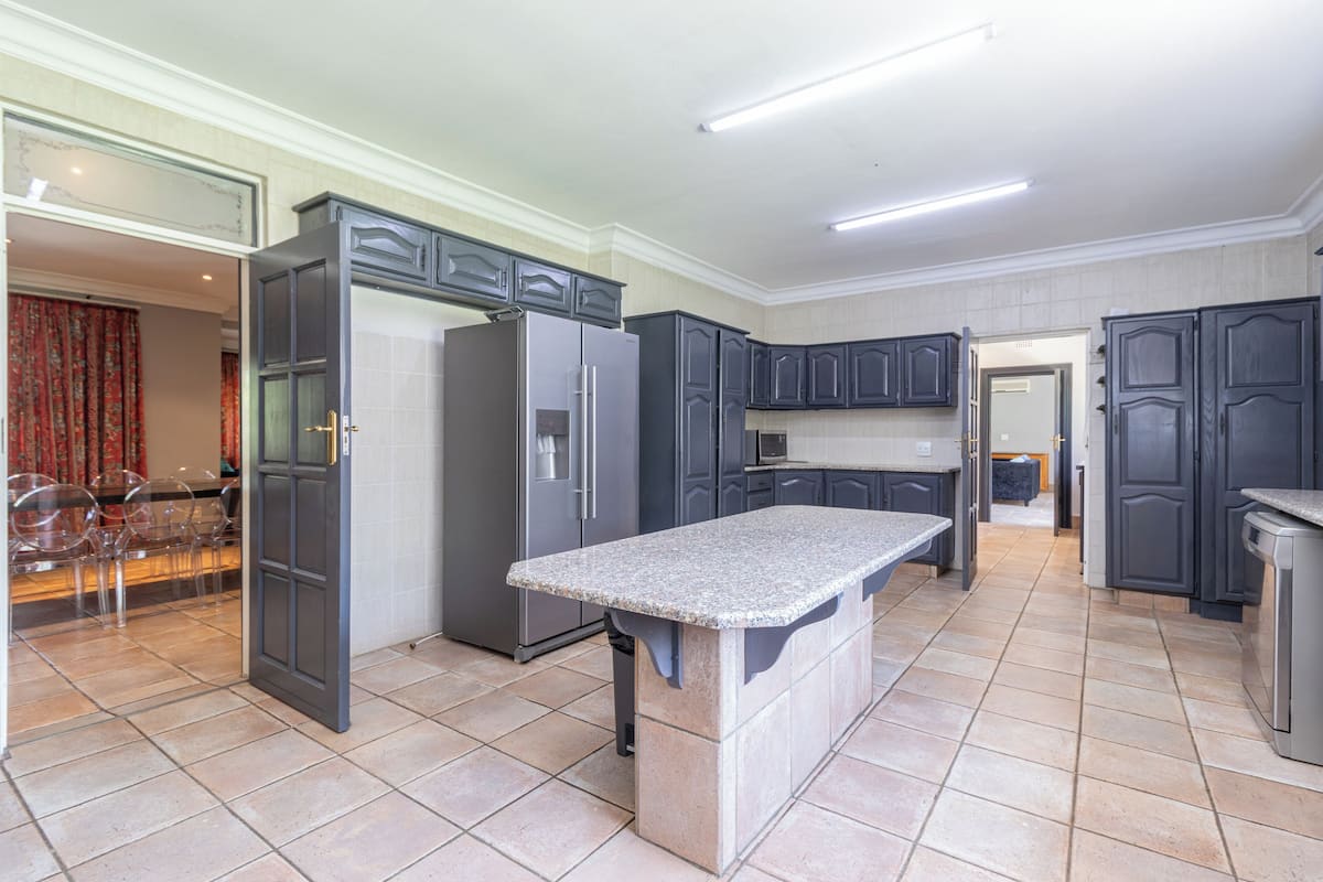 Uma cozinha espaçosa com armários escuros, bancada em granito e geladeira.