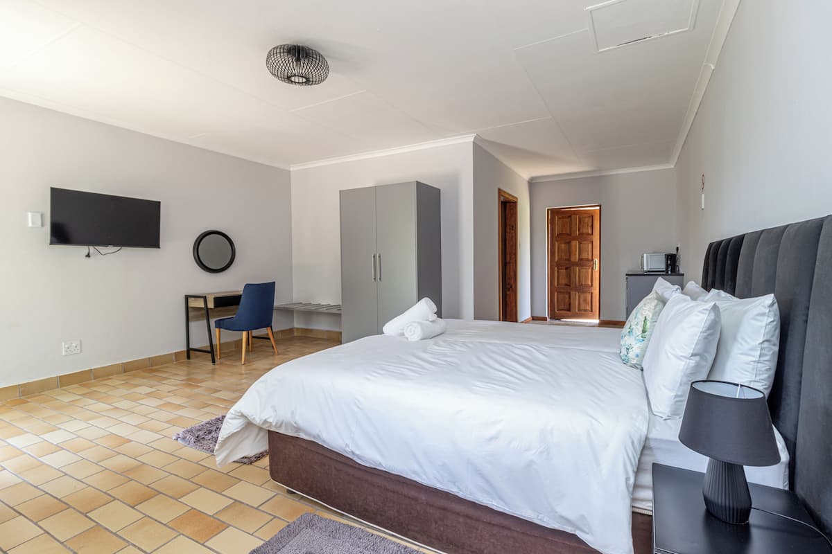 Quarto com cama grande, escrivaninha, cadeira, televisão e guarda-roupa.