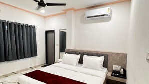 Quarto moderno com uma cama grande, um ventilador de teto, aparelho de ar condicionado e uma mesinha de cabeceira com cafeteira.
