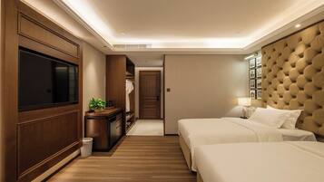 Quarto de hotel com duas camas, televisão, escrivaninha e guarda-roupa.