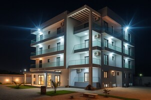 Um edifício com vários andares, varandas, janelas amplas e uma entrada bem iluminada.