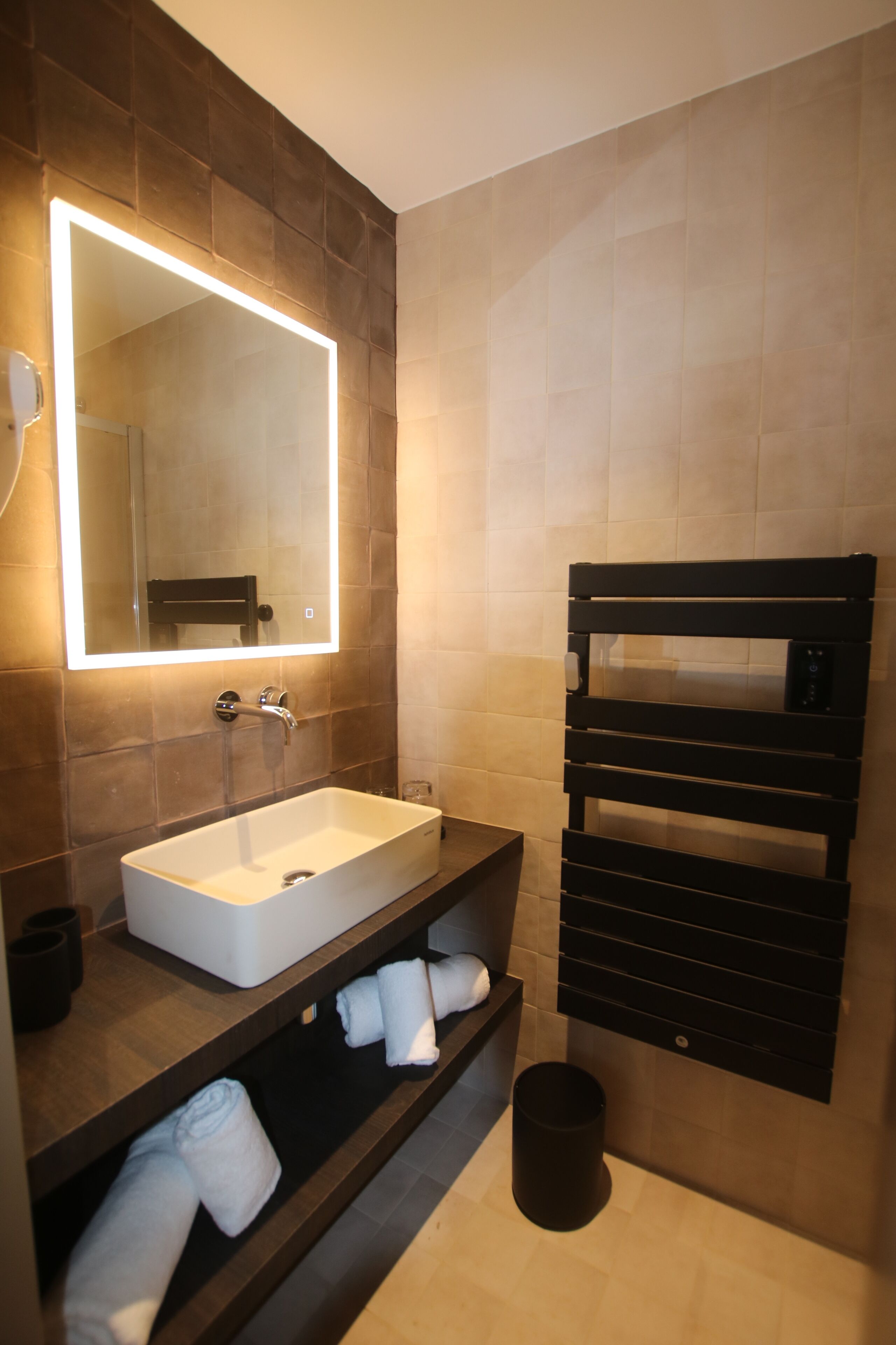 Um banheiro moderno com um espelho grande, uma pia branca e um porta-toalhas.