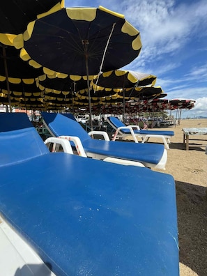 Perto da praia, espreguiçadeiras, guarda-sóis de praia