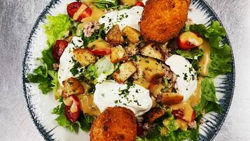 Prato de comida com salada, croutons e molho cremoso.