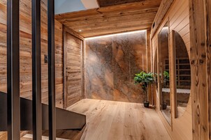 Interior em madeira com parede de mármore, uma escadaria e um vaso de planta.