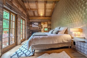 Um quarto aconchegante com uma cama grande, uma janela com vários painéis, teto de madeira e parede com padrão.