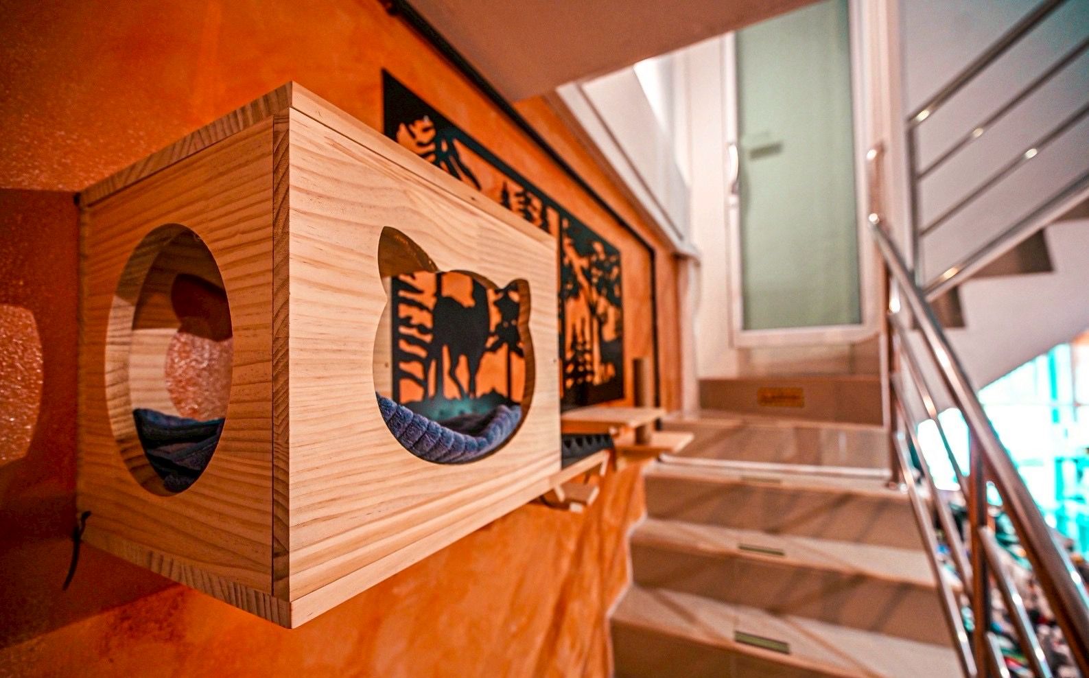 Estrutura de madeira com desenhos recortados, possivelmente um elemento decorativo ou um móvel, em ambiente interno moderno com escadaria.