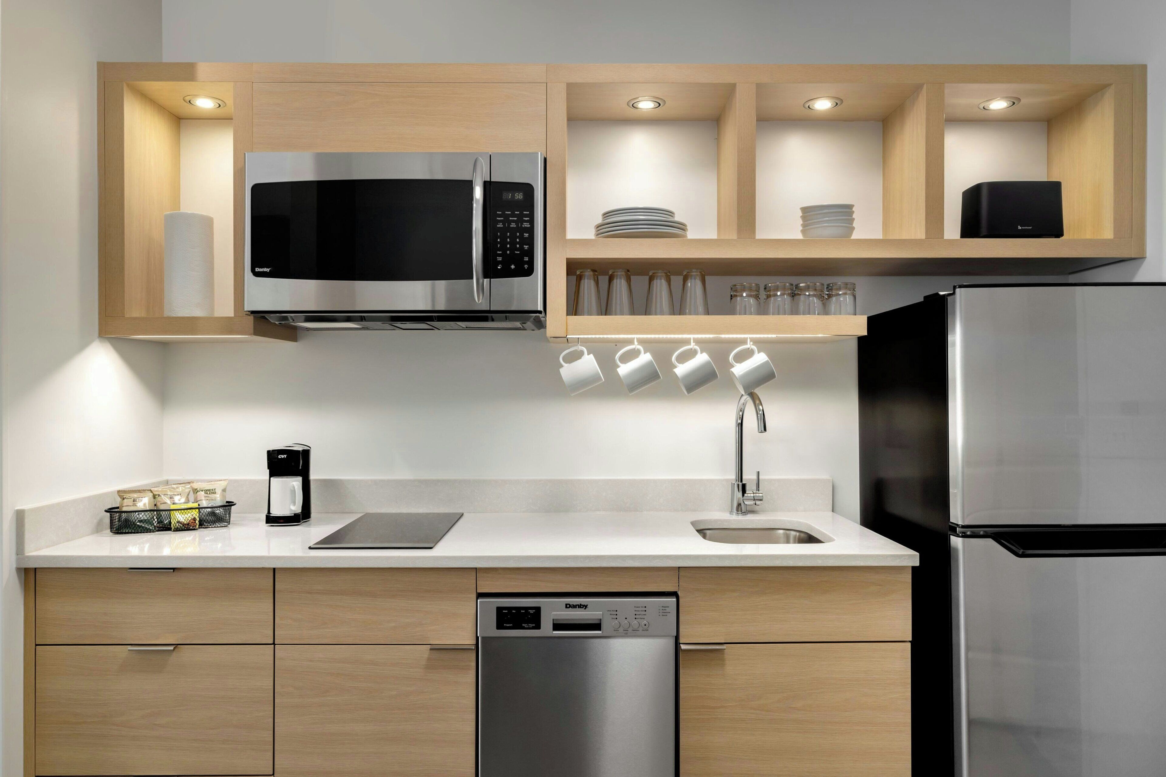 Uma cozinha moderna equipada com micro-ondas, cafeteira, máquina de lavar louça e frigorífico.