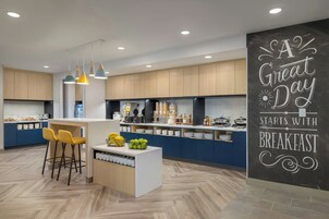 Cozinha moderna com ilha central, banquetas e parede de lousa com uma mensagem de café da manhã.