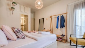 Quarto com cama, cadeira de madeira, luminária pendente, espelho e cabideiro.
