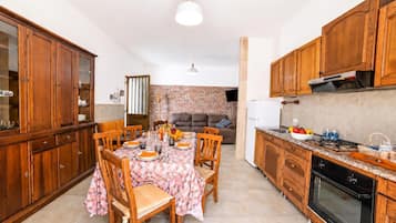 Uma cozinha com armários de madeira, uma mesa de jantar posta para quatro pessoas e uma parede de tijolos ao fundo.