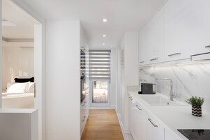 Uma cozinha moderna com armários brancos, bancada de mármore e pia embutida.