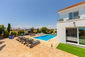 Uma casa moderna com piscina, mobiliário de exterior e um jardim bem cuidado.