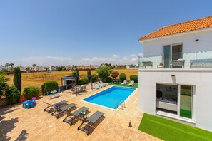 Uma villa moderna com piscina, área de estar externa e vista para a paisagem ao redor.