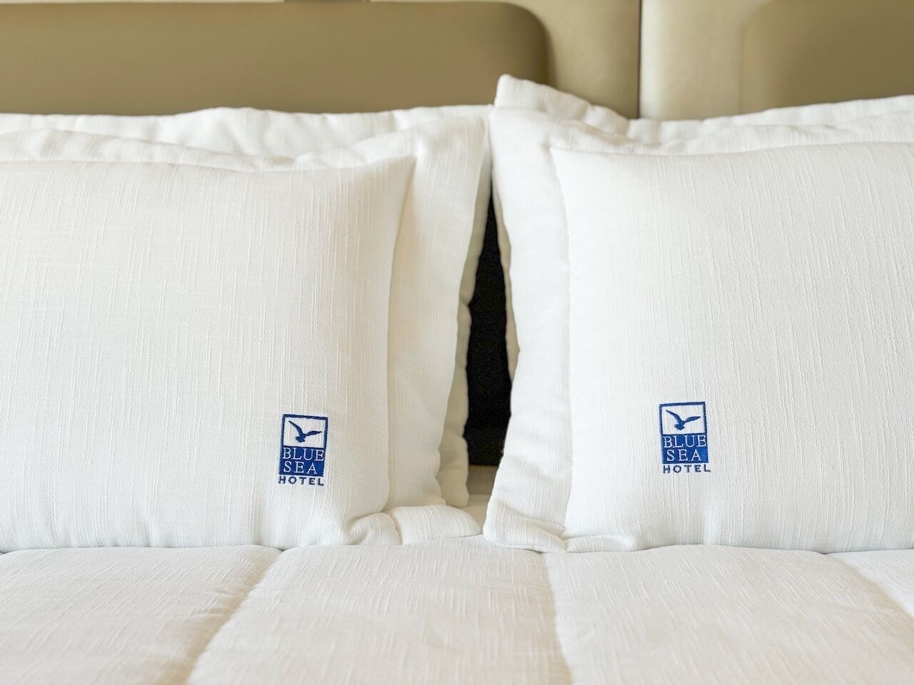 Duas almofadas brancas com um logotipo numa cama.
