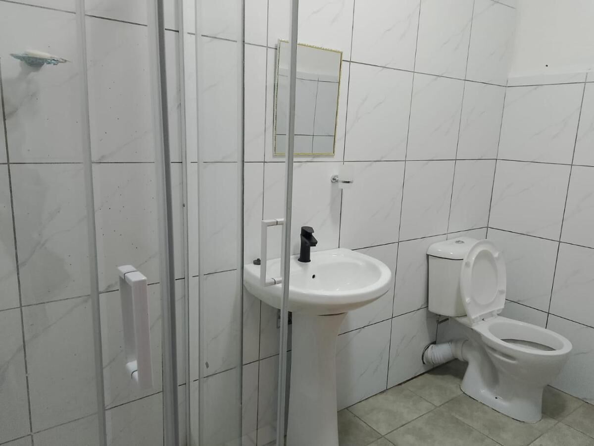 Casa de banho com lavatório branco, sanita e cabine de duche em vidro.