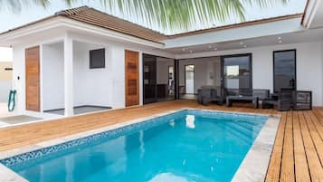 Uma casa moderna com piscina, deck de madeira e mobiliário para área externa.