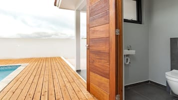 Um deck de madeira com piscina, um banheiro com pia e vaso sanitário, e uma porta de madeira grande.