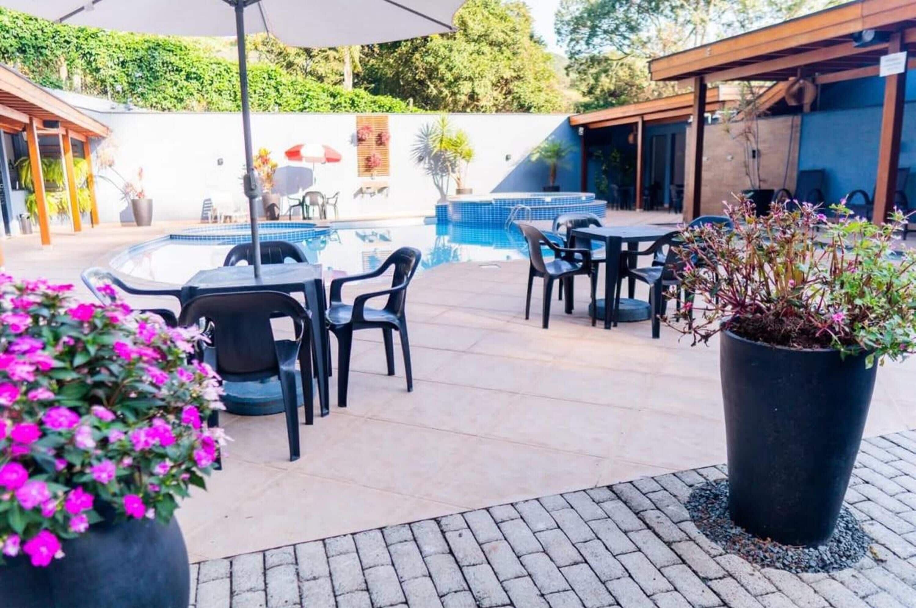 Uma área de pátio ao ar livre com piscina, mobiliário de jardim e plantas em vasos.