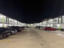 Um motel com vários andares, um estacionamento cheio de carros e uma passarela central.